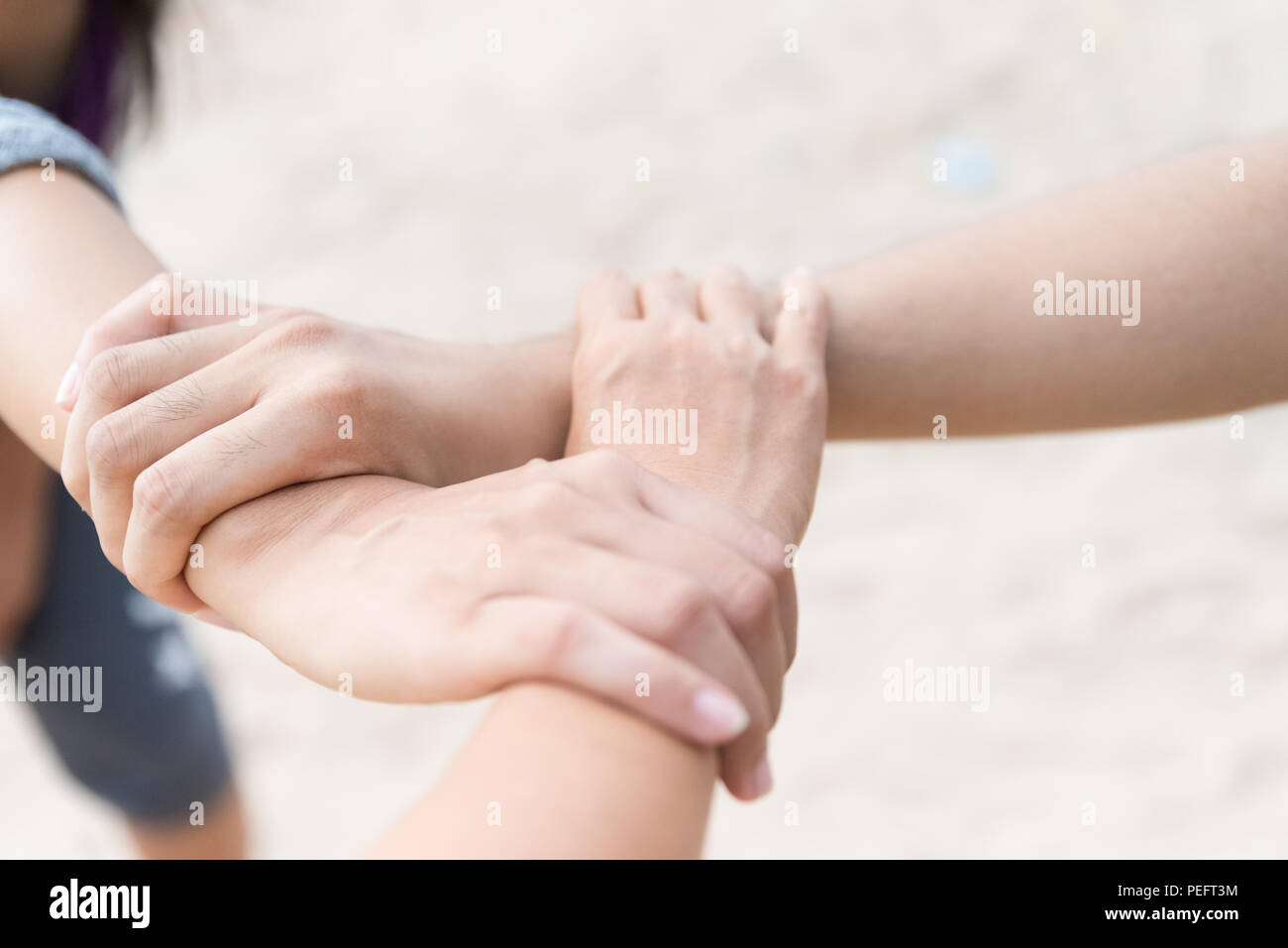 Three people join hands together on white sand beach background ...