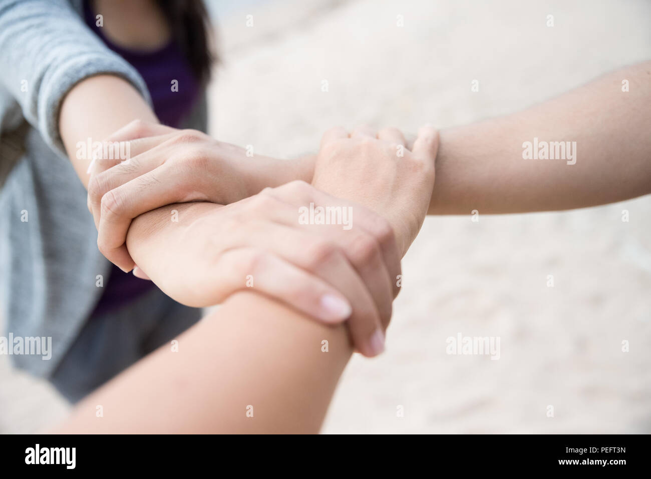 Three people join hands together on white sand beach background ...