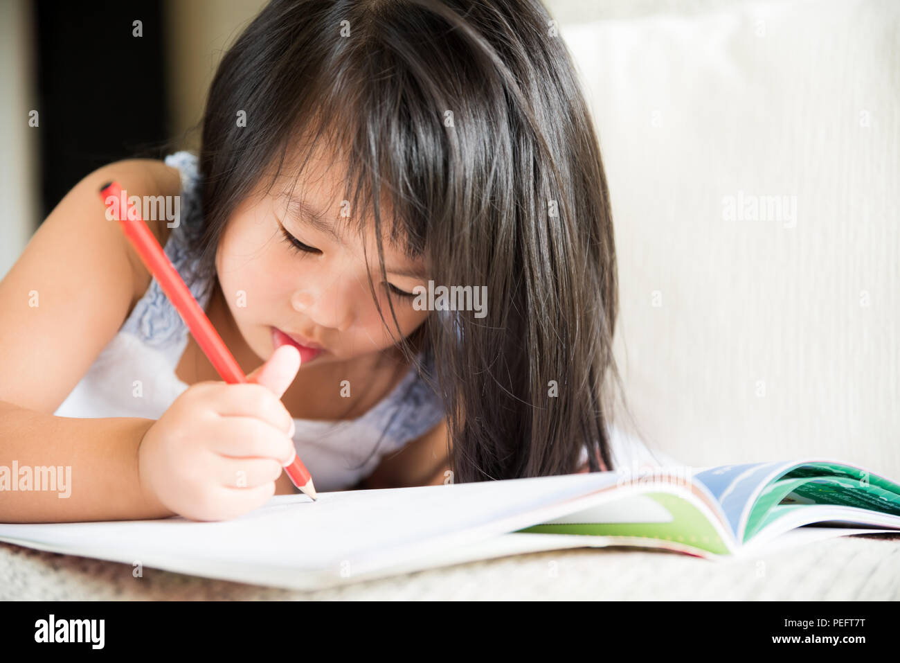 Happy cute little girl smiling and holding red pencil and drawing ...