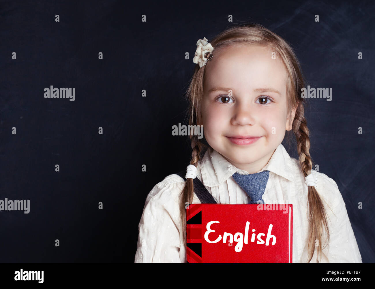 Little girl student with english book near blackboard in the classroom ...