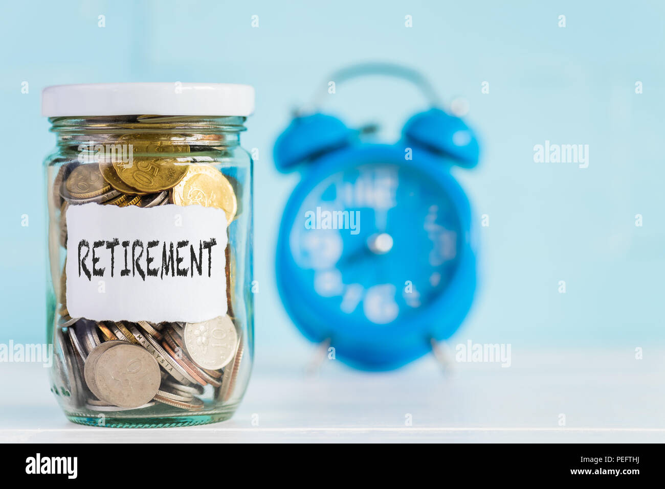 Glass jar coins with alarm clock background for retirement concept ...