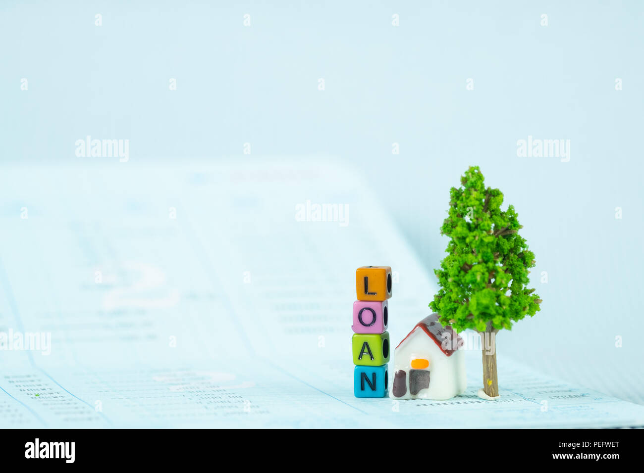 LOAN text and small model house and little tree with notebook, savings ...