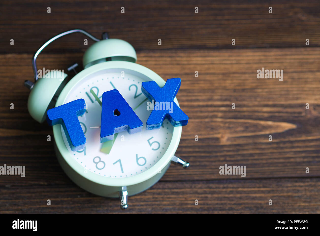 Time to pay TAX concept. TAX alphabet and vintage alarm clock on wooden ...