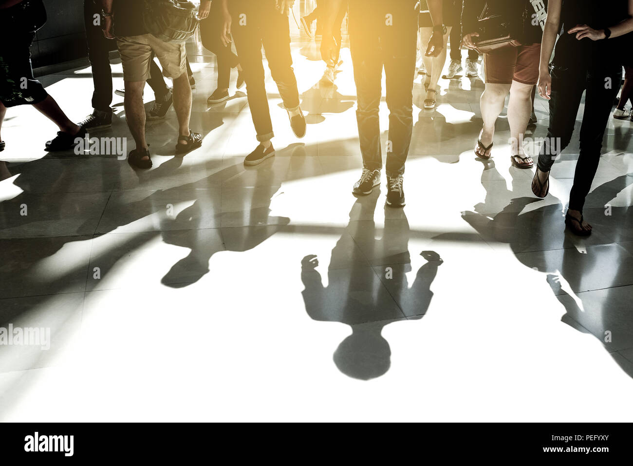 People walking and sunlight shining from behind making shadow on the ...