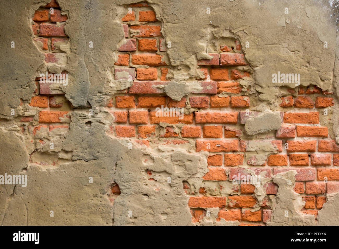 crumbling render or plaster coming off of red brick wall. Building ...