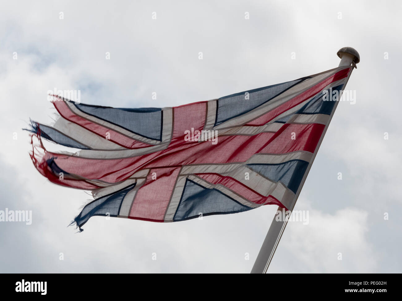 a tattered or battered union flag or union jack flying against a cloudy ...