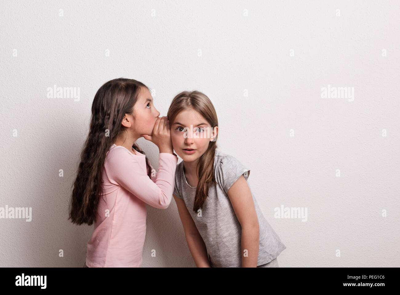 A small girl whispering something in an ear of her friend Stock Photo ...
