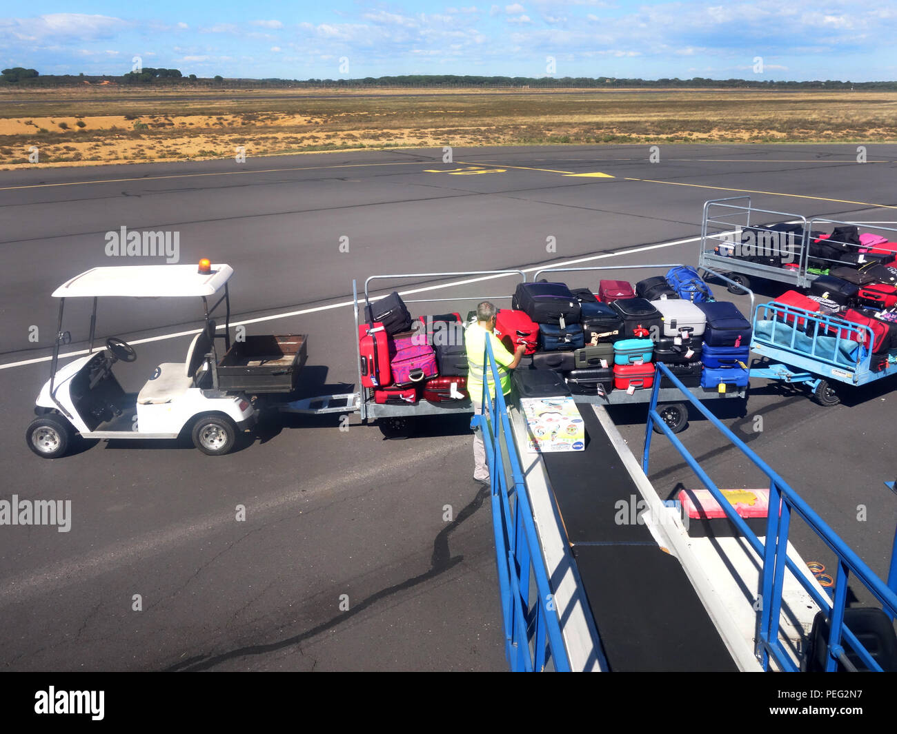 Airport handler loading baggage being put on a conveyor into a plane at ...