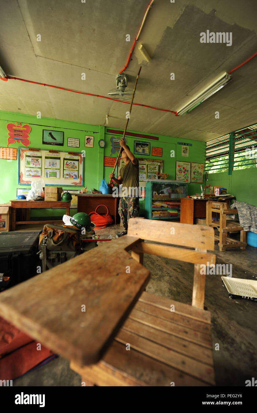 A member of the Armed Forces of the Philippines paints a class room at Dao Elementary school in ...