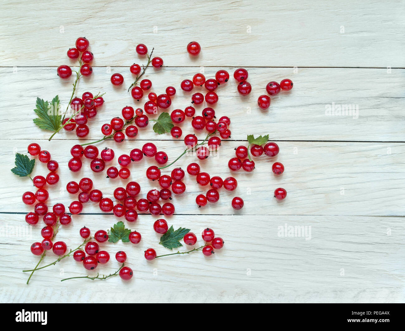 Fresh large red currant berries are scattered on a wooden background ...
