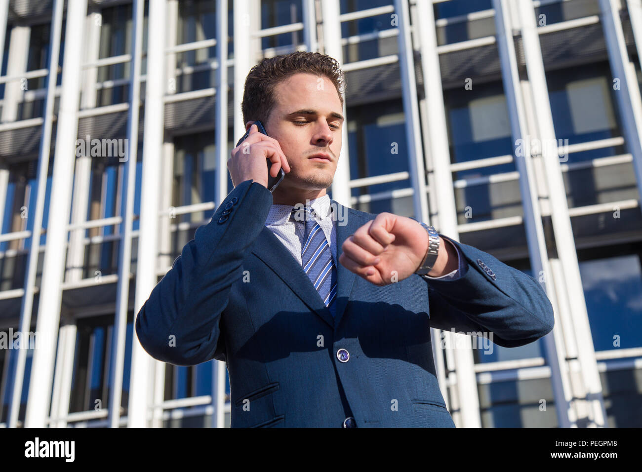Serious businessman checking time talking on phone Stock Photo - Alamy