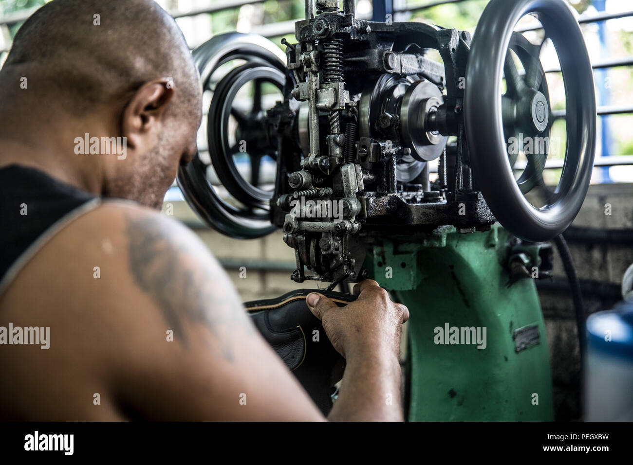 An employee at a hospital sews shoes together designed to fit ...