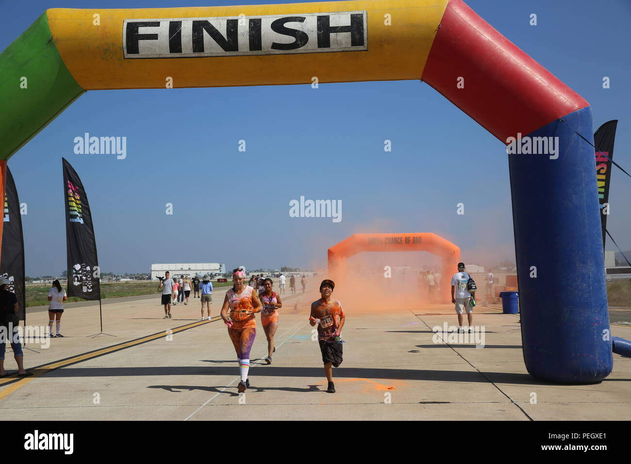 Participants cross the finish line after completing the Color Me Rad 5k ...