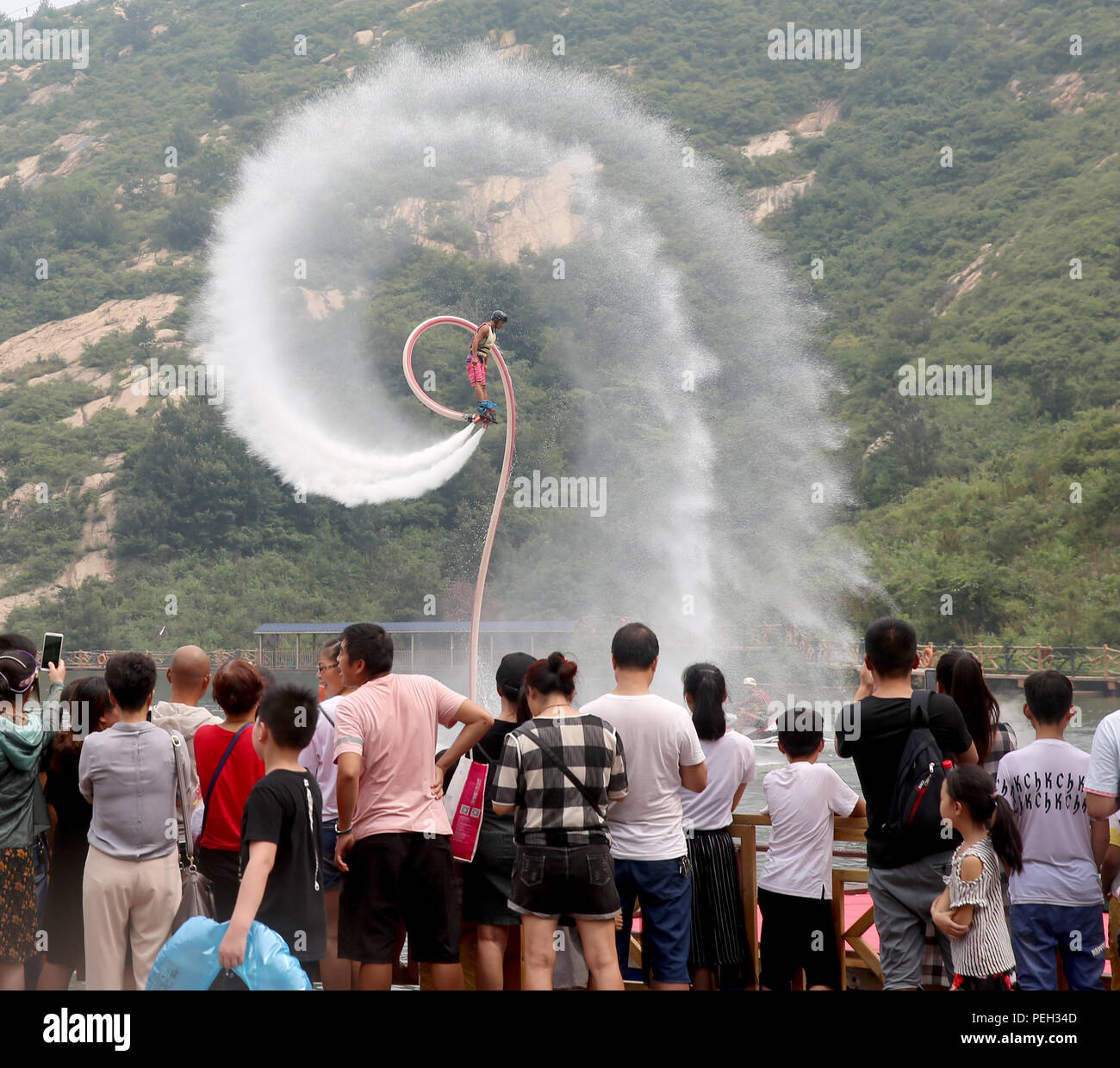 Nanyang, China. 15th Aug, 2018. Flyboard rider performs acrobatics with ...