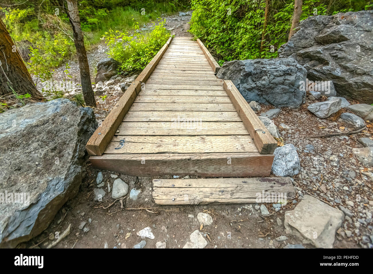 Wooden bridge with no rails over stream Stock Photo - Alamy