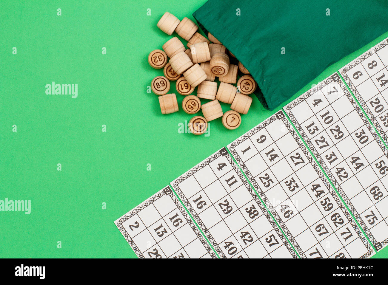 Wooden lotto barrels with cloth bag and game cards on green background ...