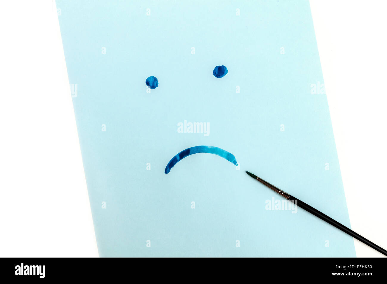 Blue, sad face hand painted on blue paper in watercolor, depression ...