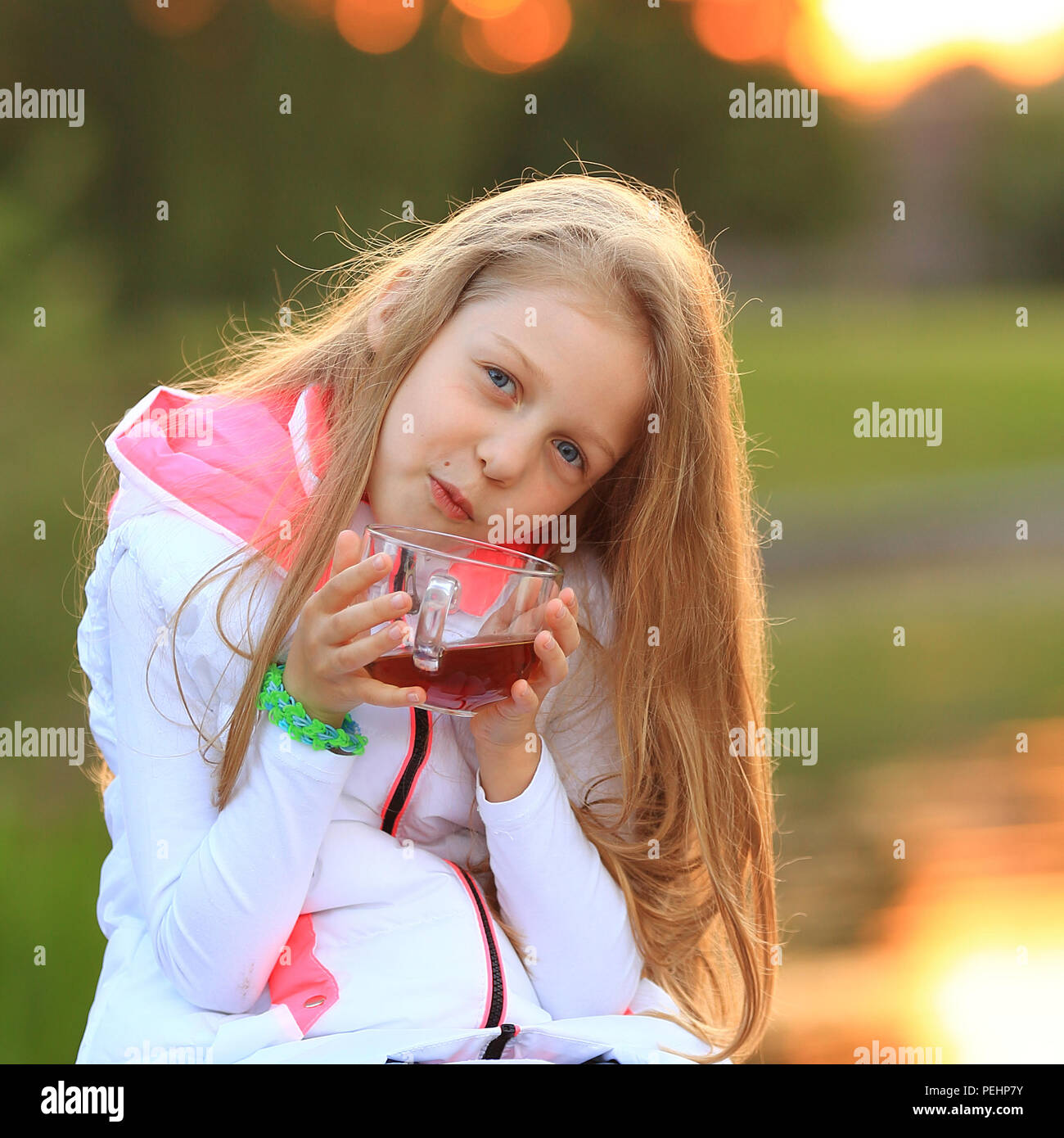 cute little girl with a Cup of tea sitting on a bench in the coo Stock ...