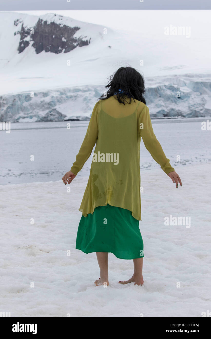 Asian tourist standing barefoot in the snow on a South Shetland Island ...