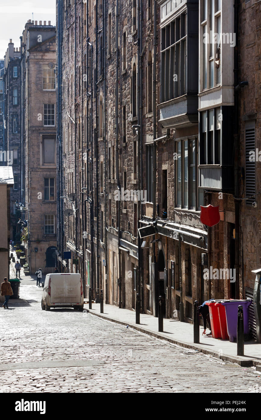 Old vintage street with dirty car and colorful garbage bins in ...