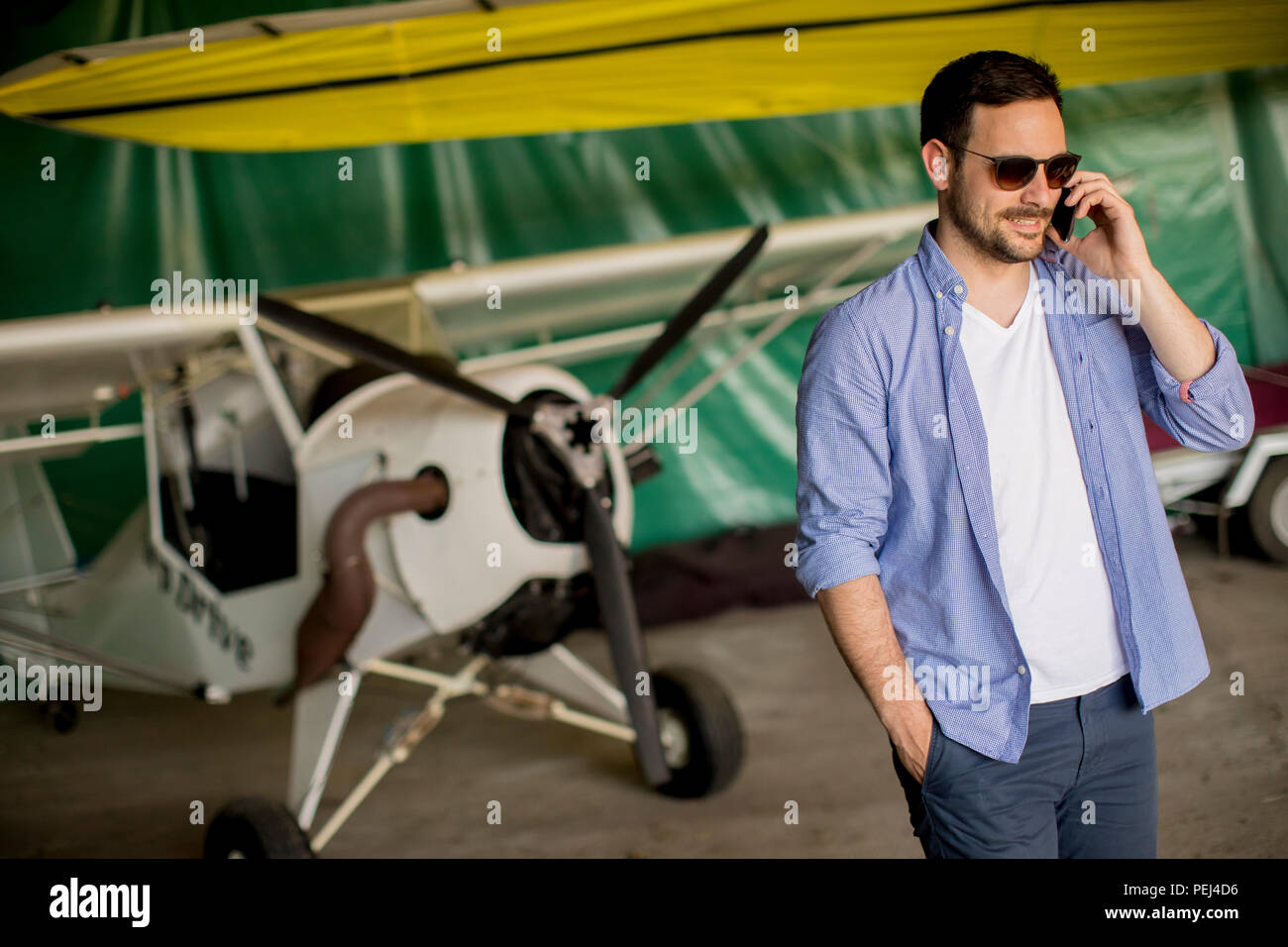 Young handsome young pilot checking airplane in the hangar and using ...