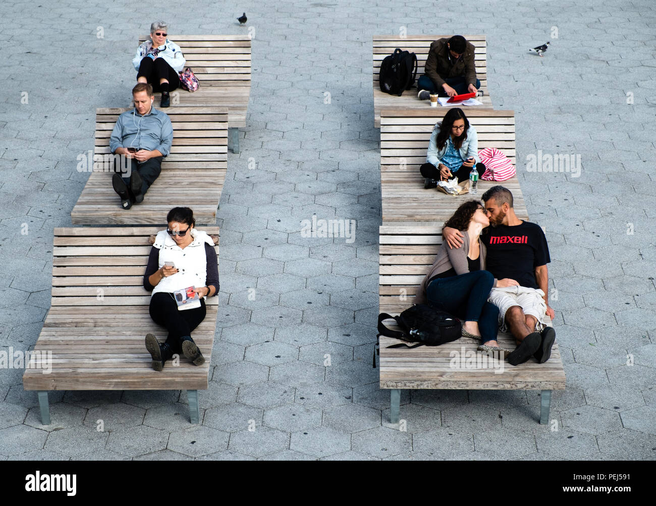 Seven people relaxing on benches performing different tasks Stock Photo ...