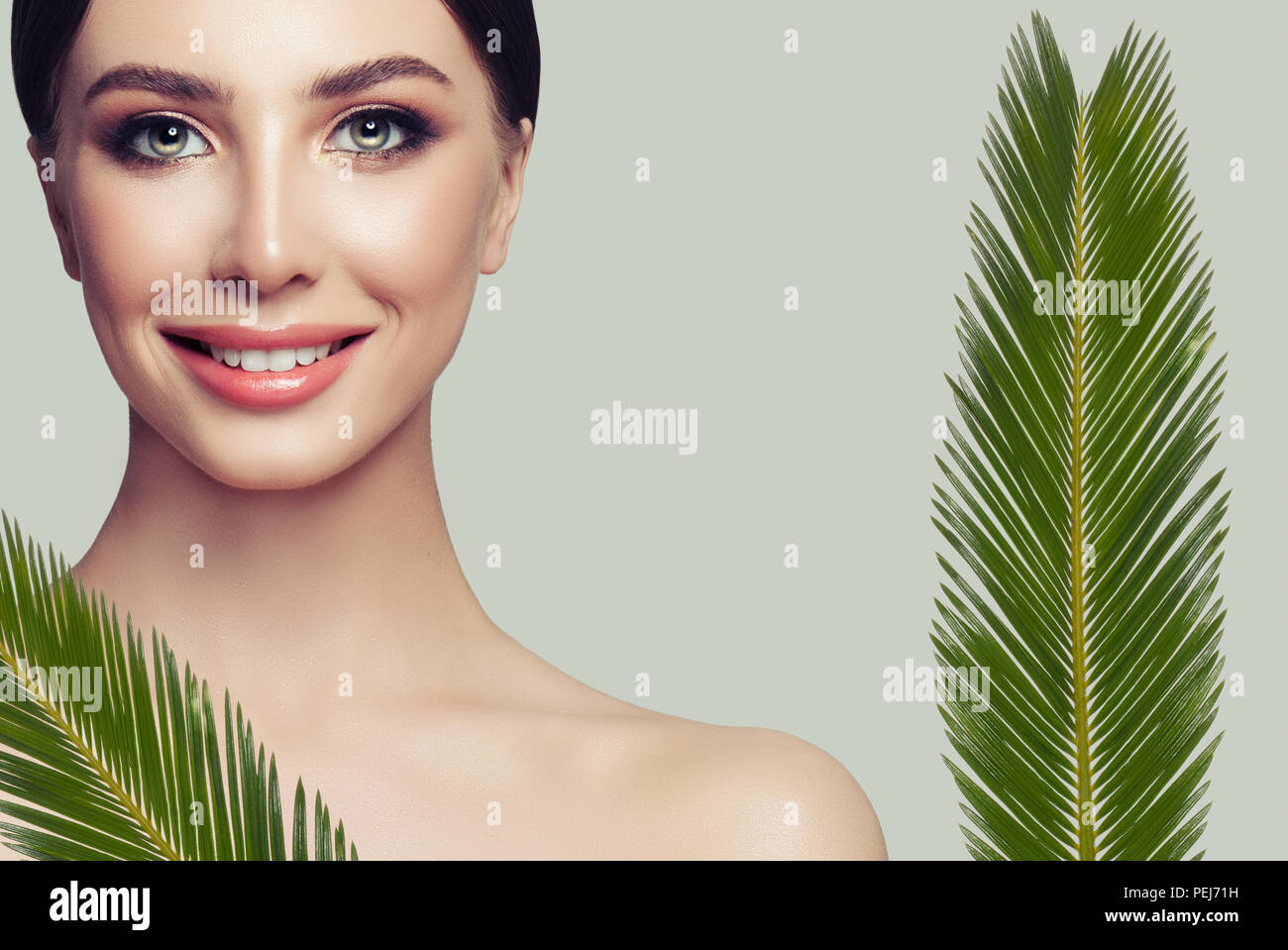 Female face and green leaves. Spa woman model with healthy skin and ...