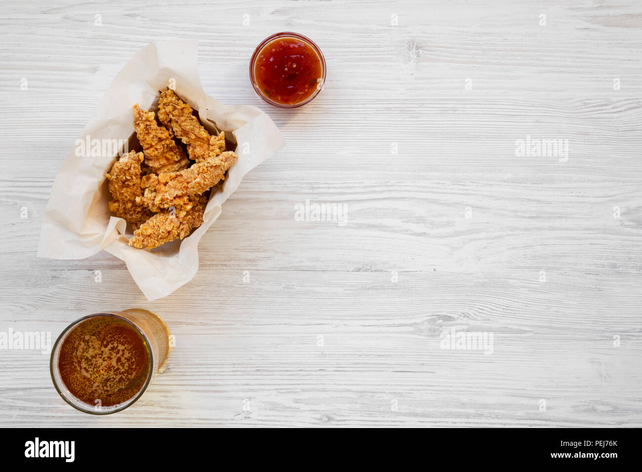 Fried chicken strips in box with sauce and cold beer, top view. Flat ...