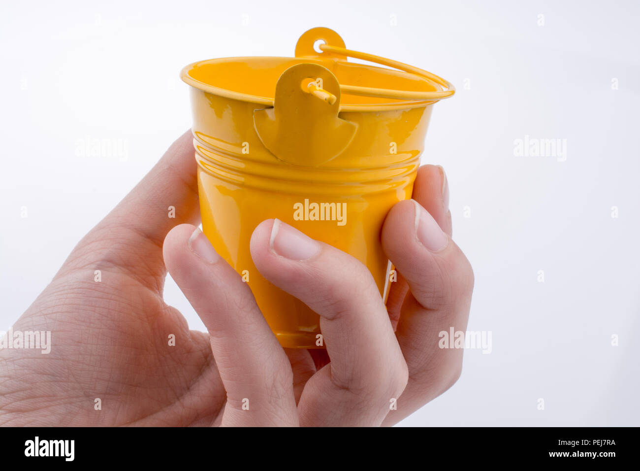 Hand holding a yellow bucket on a white background Stock Photo - Alamy