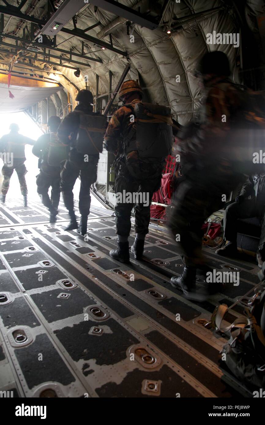 Paratroopers walk off the tail of the aircraft that is flying over ...