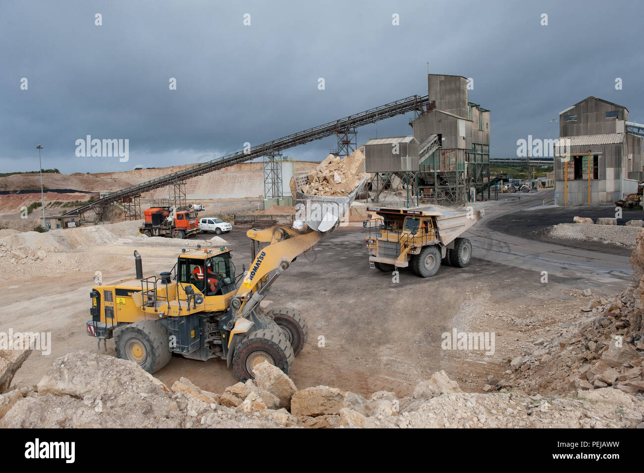Excavating and picking up mined aggregate from the quarry floor, in a ...