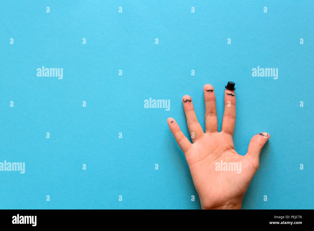 Fingers with a mustache and cylinder on blue paper background. Movember ...