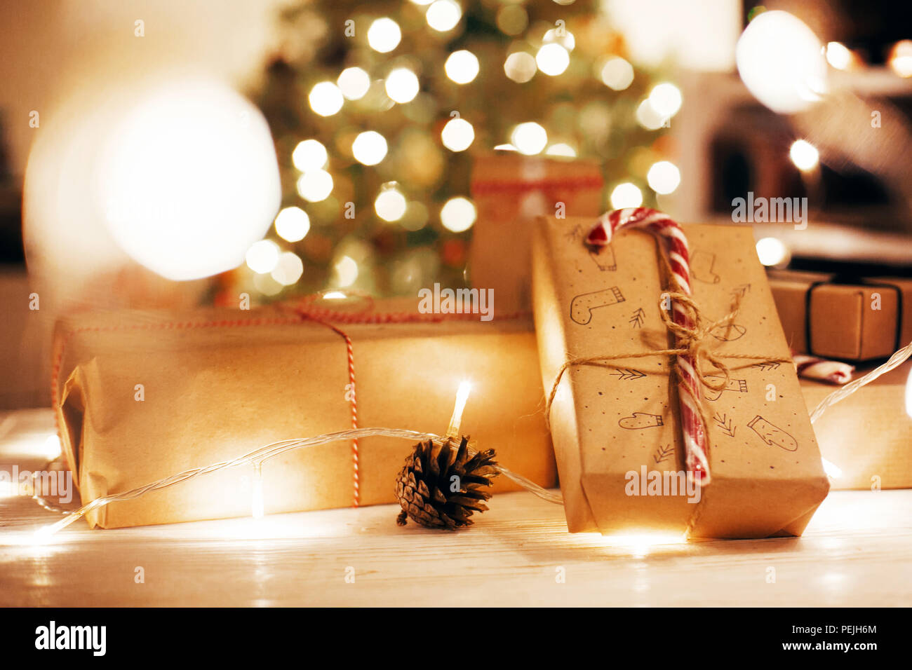 stylish christmas presents in lights on wooden table on background of ...