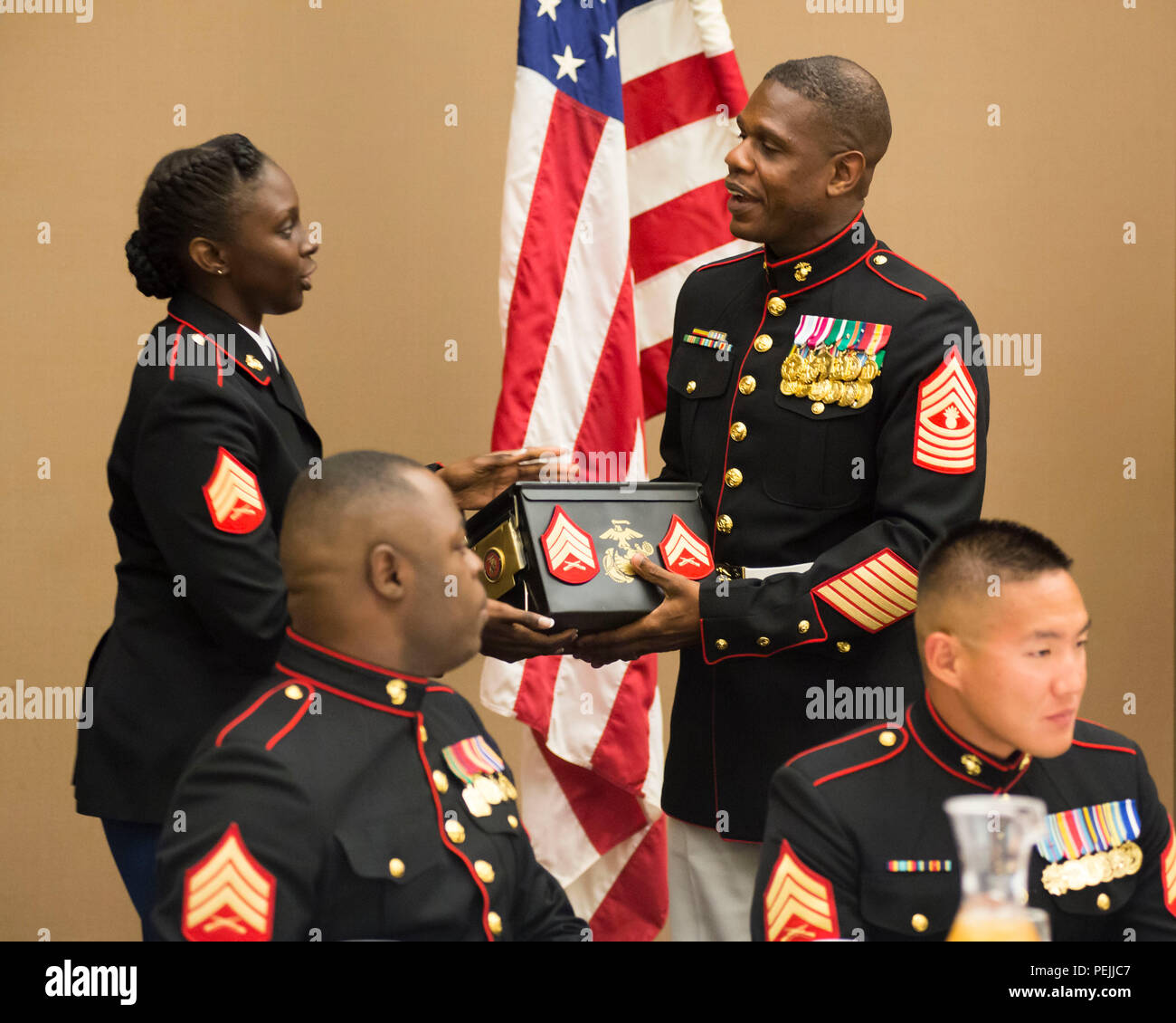 U.S. Marine Sgt. Kyra Dotson hands Master Gunnery Sgt. Shawn Hall a decorated ammo can at the ...