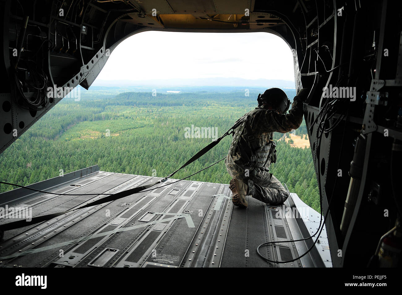 A crew chief looks out the back of a Chinook helicopter during ...