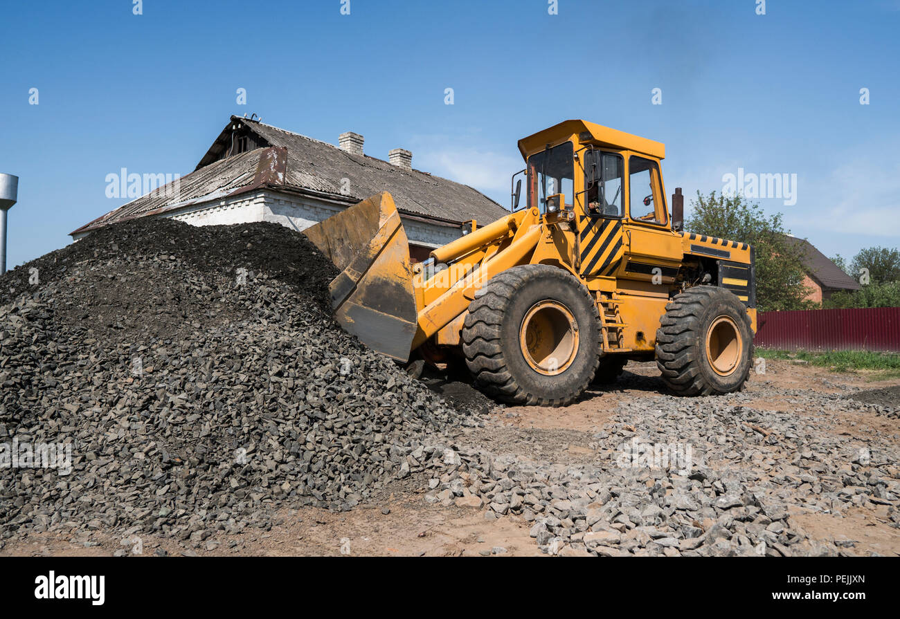 Yellow loader uploadind bucket with stone gravel during road ...