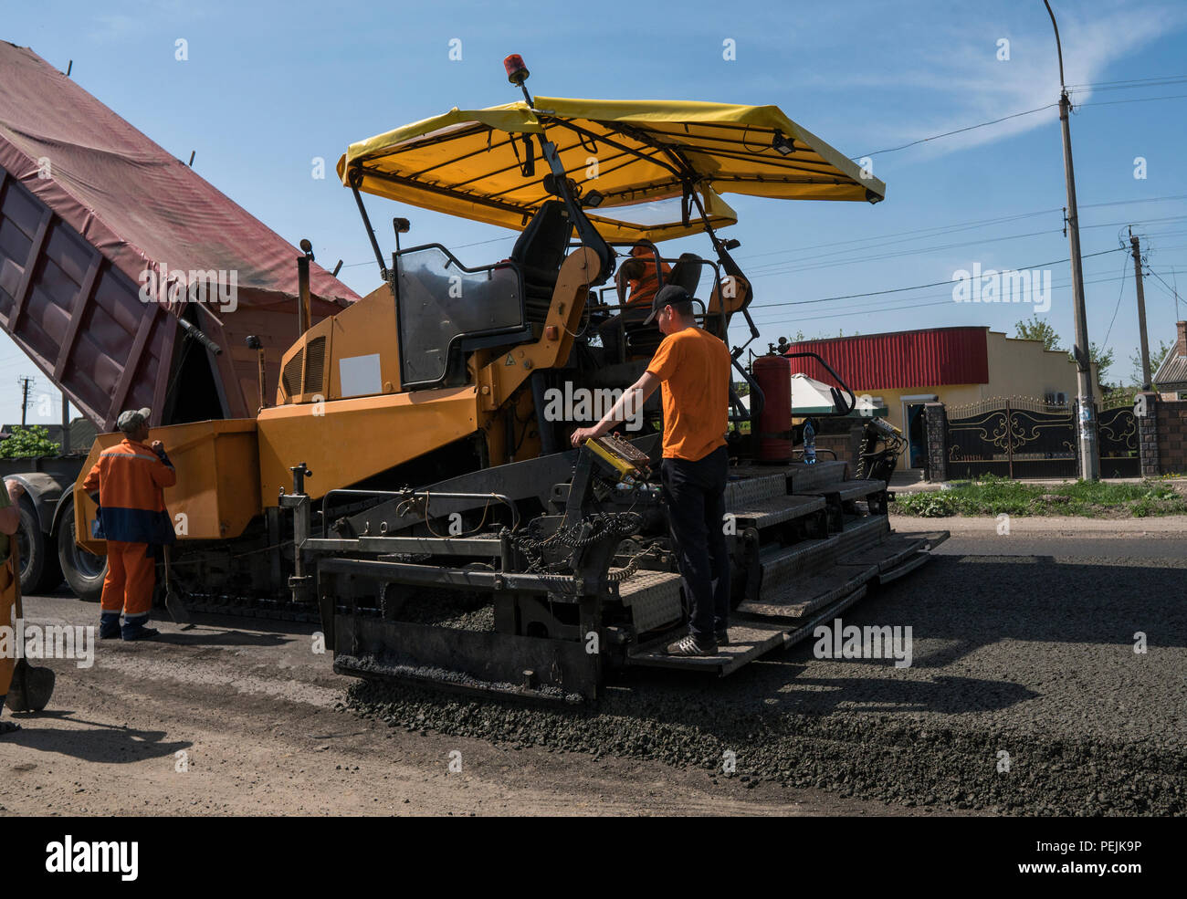Worker operating asphalt paver machine during road construction and ...