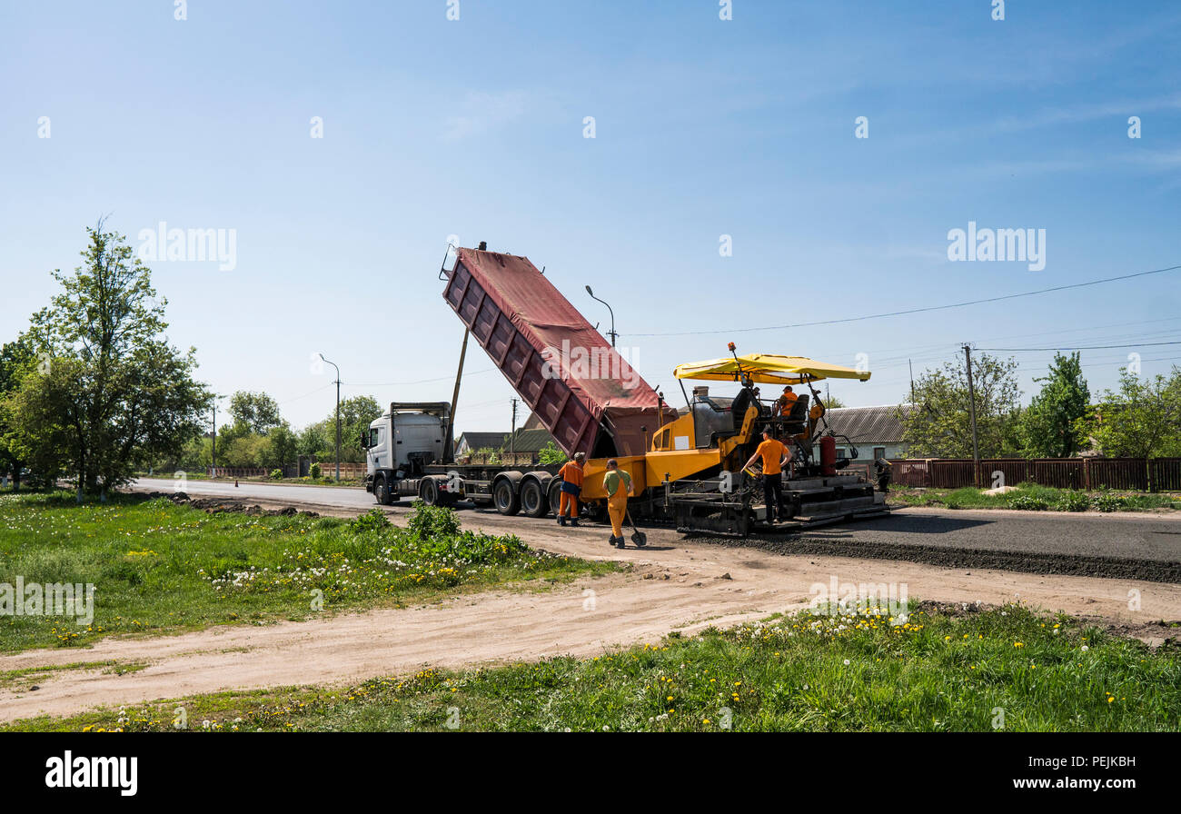 Worker operating asphalt paver machine during road construction and ...
