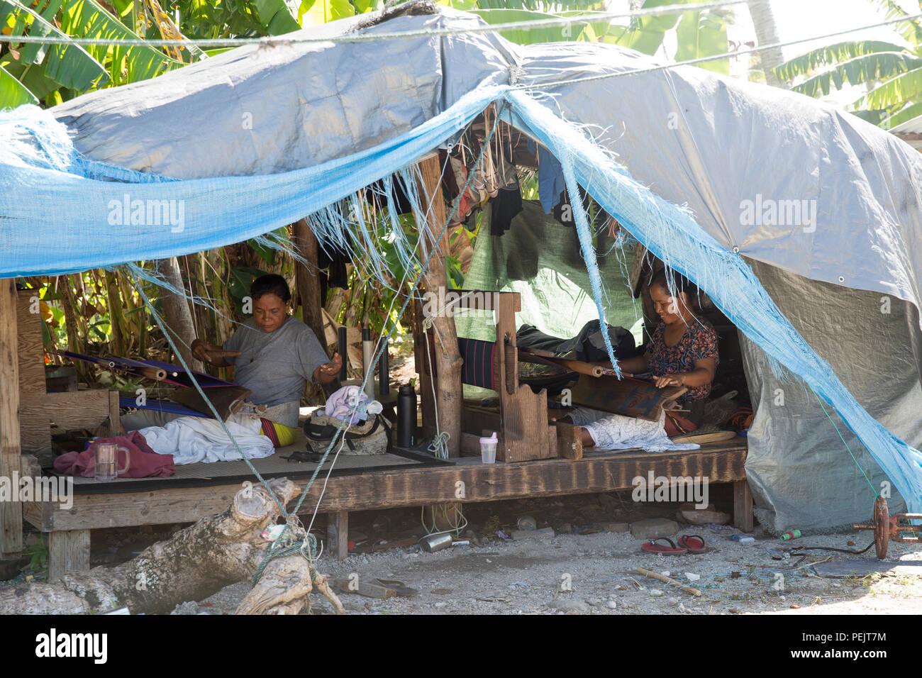 Ladies work at a house covered a plastic tarp at Falalop Island, Ulithi ...