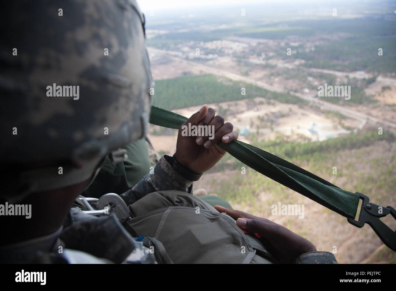 A U.S. Army paratrooper holds the door strap of a UH-60 Black Hawk at ...