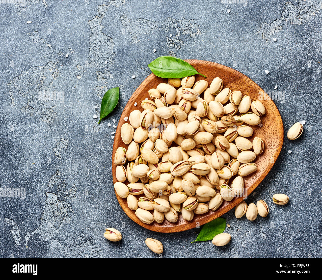 Salted Pistachios nuts with green leaves and scoop. Top view of snacks Stock Photo - Alamy
