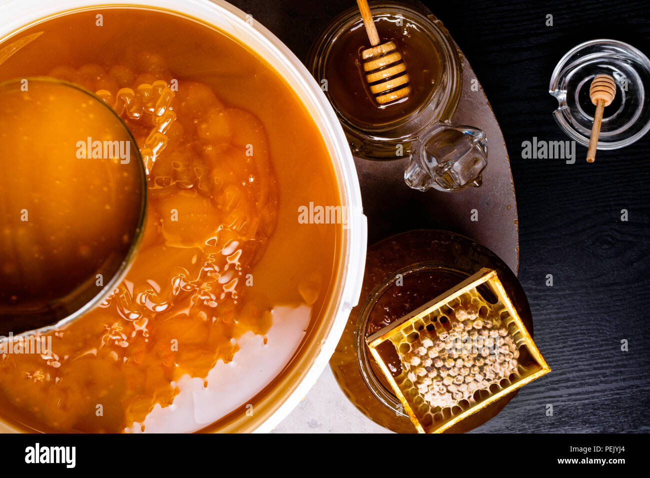 fresh honey in white bucket and in glass jar, with honeycomb, wooden ...