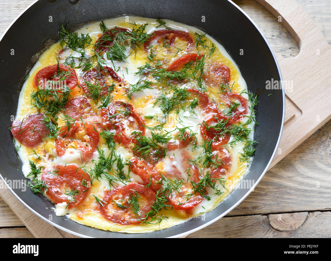 Rustic style. Scrambled eggs with tomatoes and dill in a frying pan ...