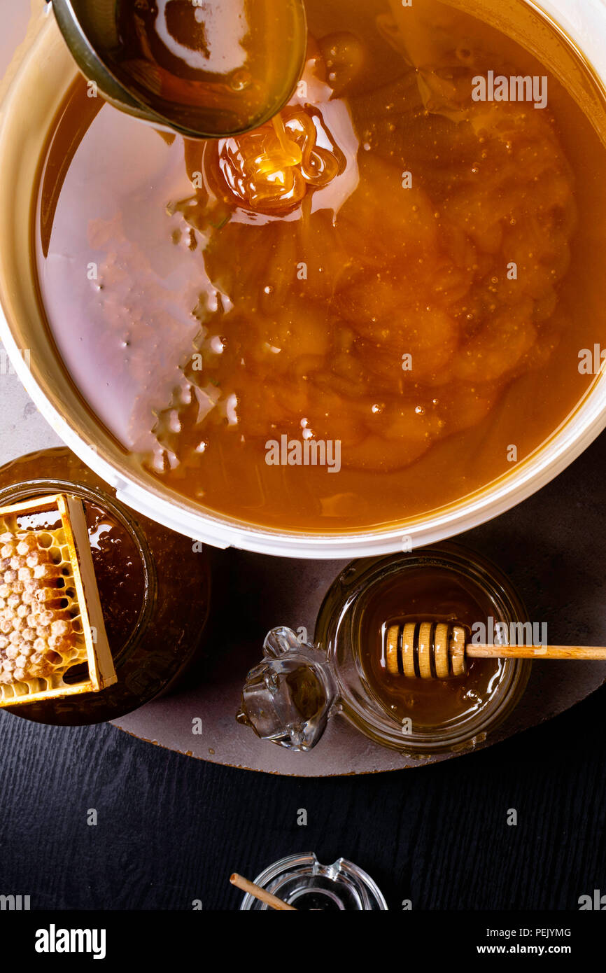 fresh honey in white bucket and in glass jar, with honeycomb, wooden ...