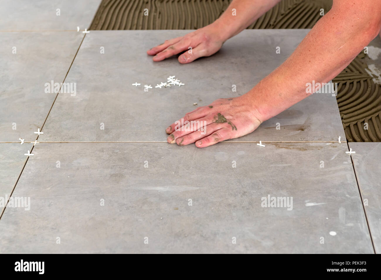 The hands of the tiler are laying the ceramic tile on the floor Stock ...