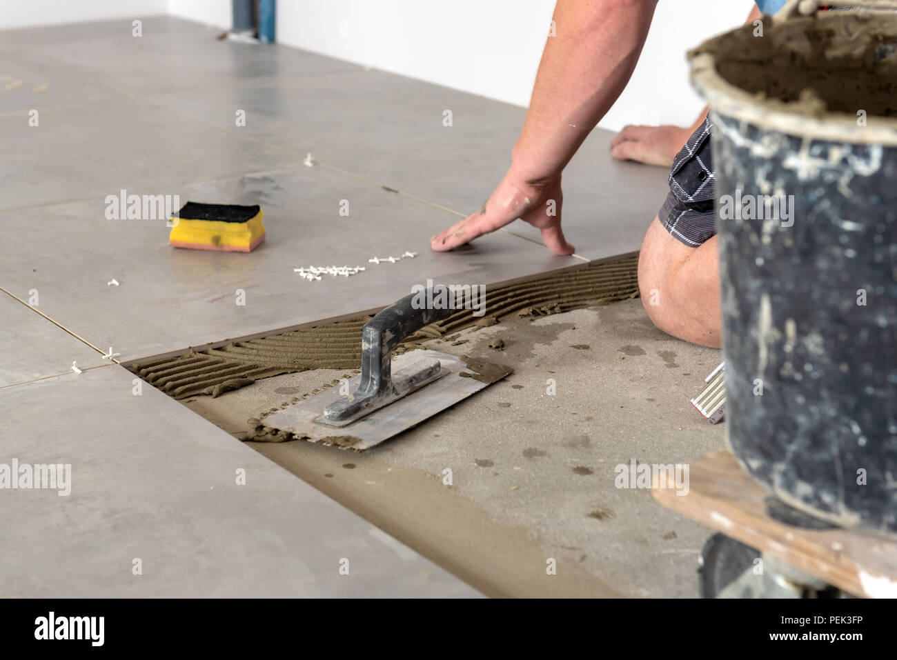 The hands of the tiler are laying the ceramic tile on the floor Stock ...