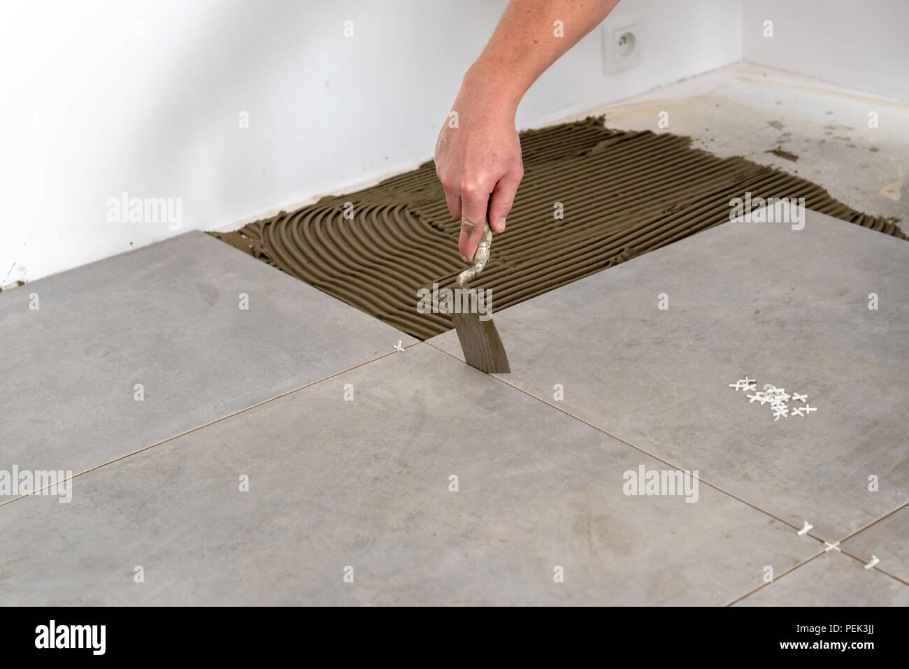 The hands of the tiler are laying the ceramic tile on the floor Stock ...