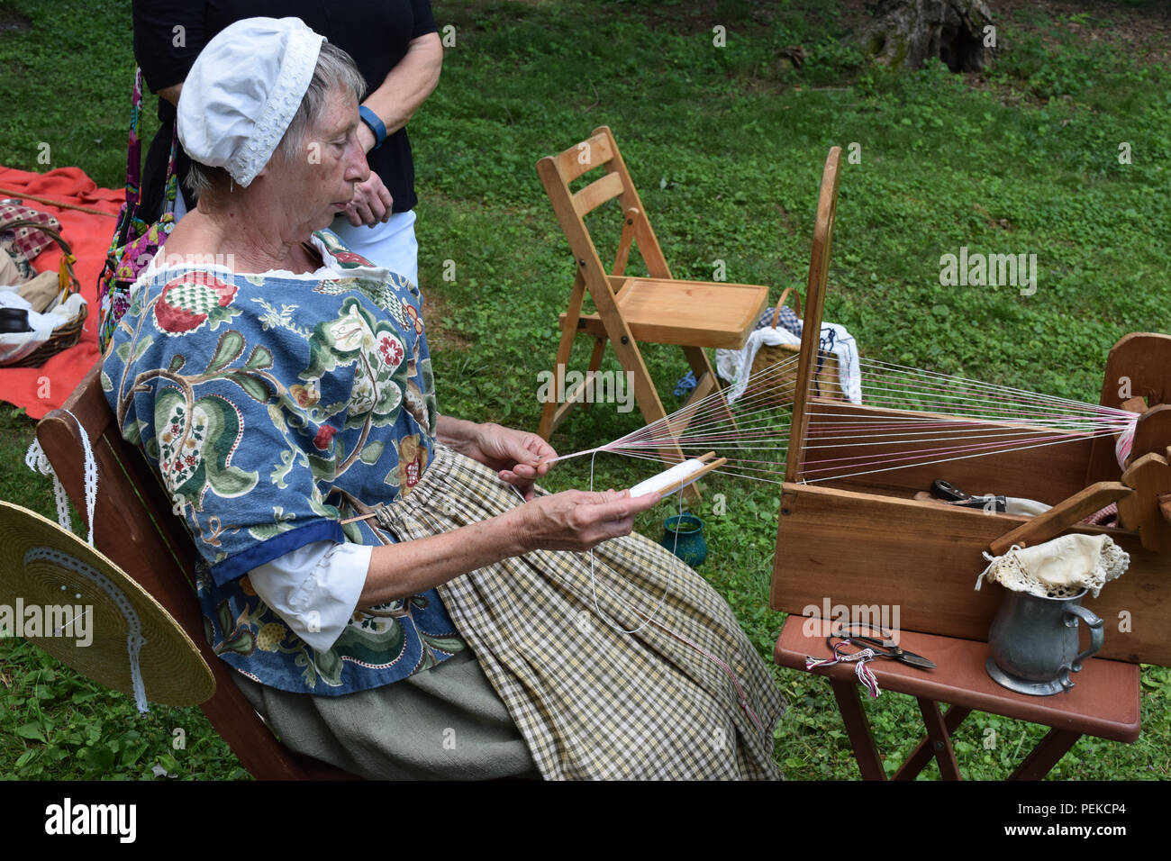 A woman giving a demonstration of using a Hand Loom from colonial times ...