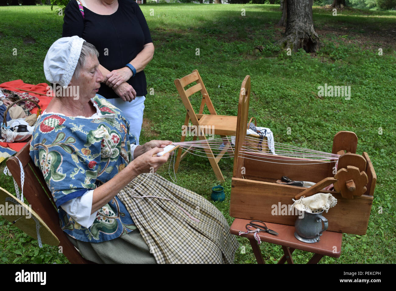 A woman giving a demonstration of using a Hand Loom from colonial times ...