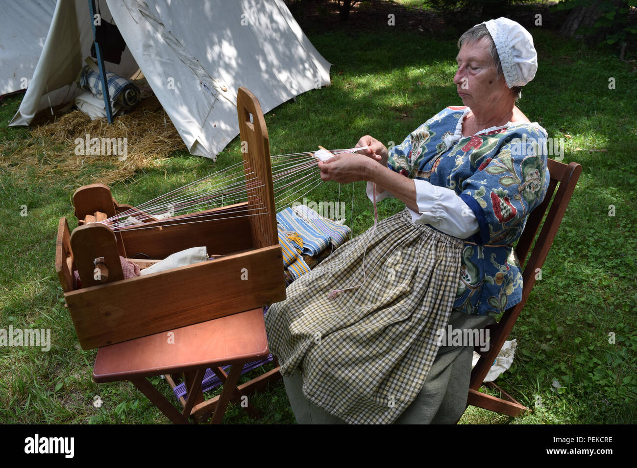 A woman giving a demonstration of using a Hand Loom from colonial times ...